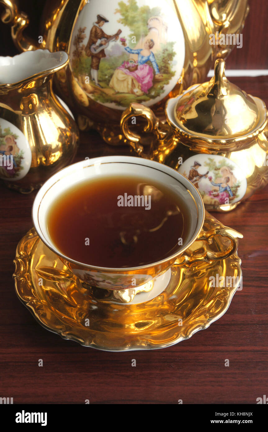 Beautiful vintage gold tea service with pictures on wood background ...