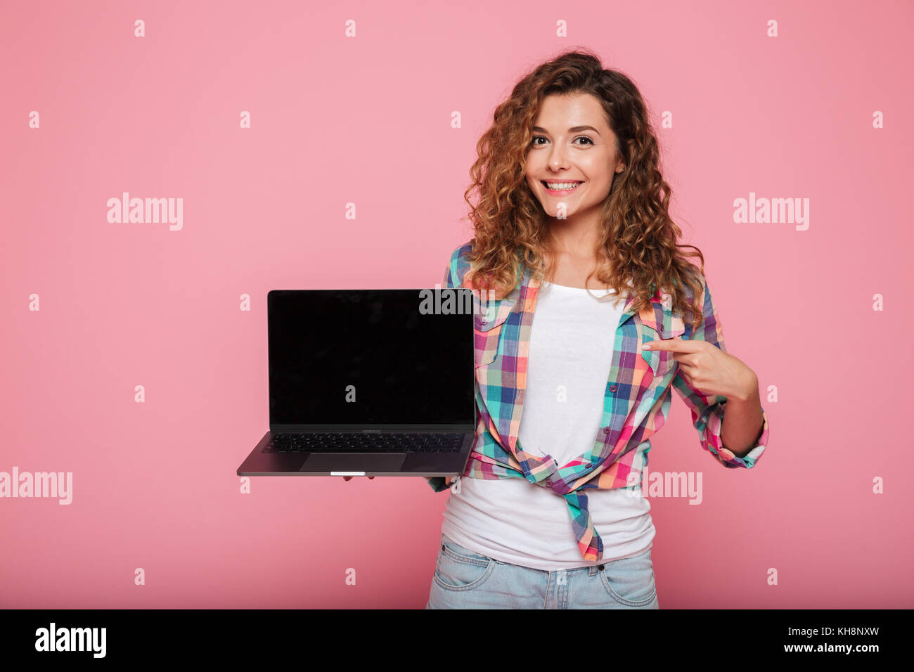 Happy caucasian woman with curly hair showing laptop computer and ...