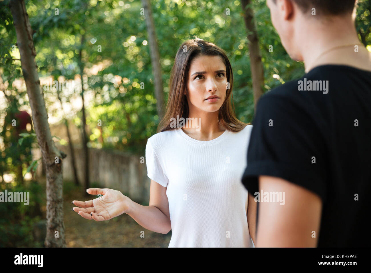 Confused young woman gesturing with hand and looking at her boyfriend ...