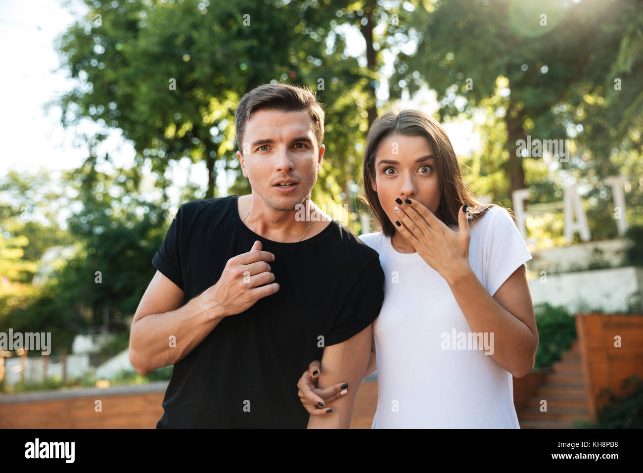 Portrait of a shocked young couple standing and looking at camera ...