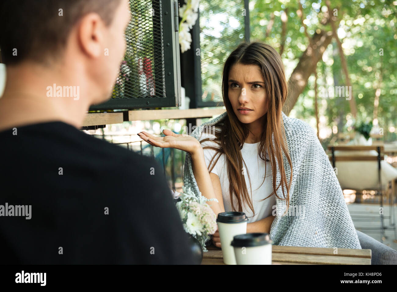 Confused young woman gesturing with hand and looking at her boyfriend ...