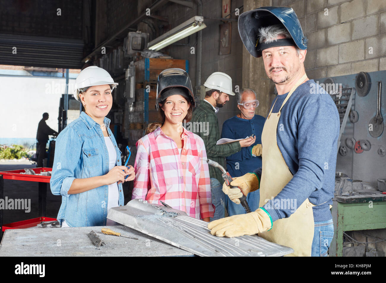 Man as welder instructor with two trainee women in metallurgy lesson ...
