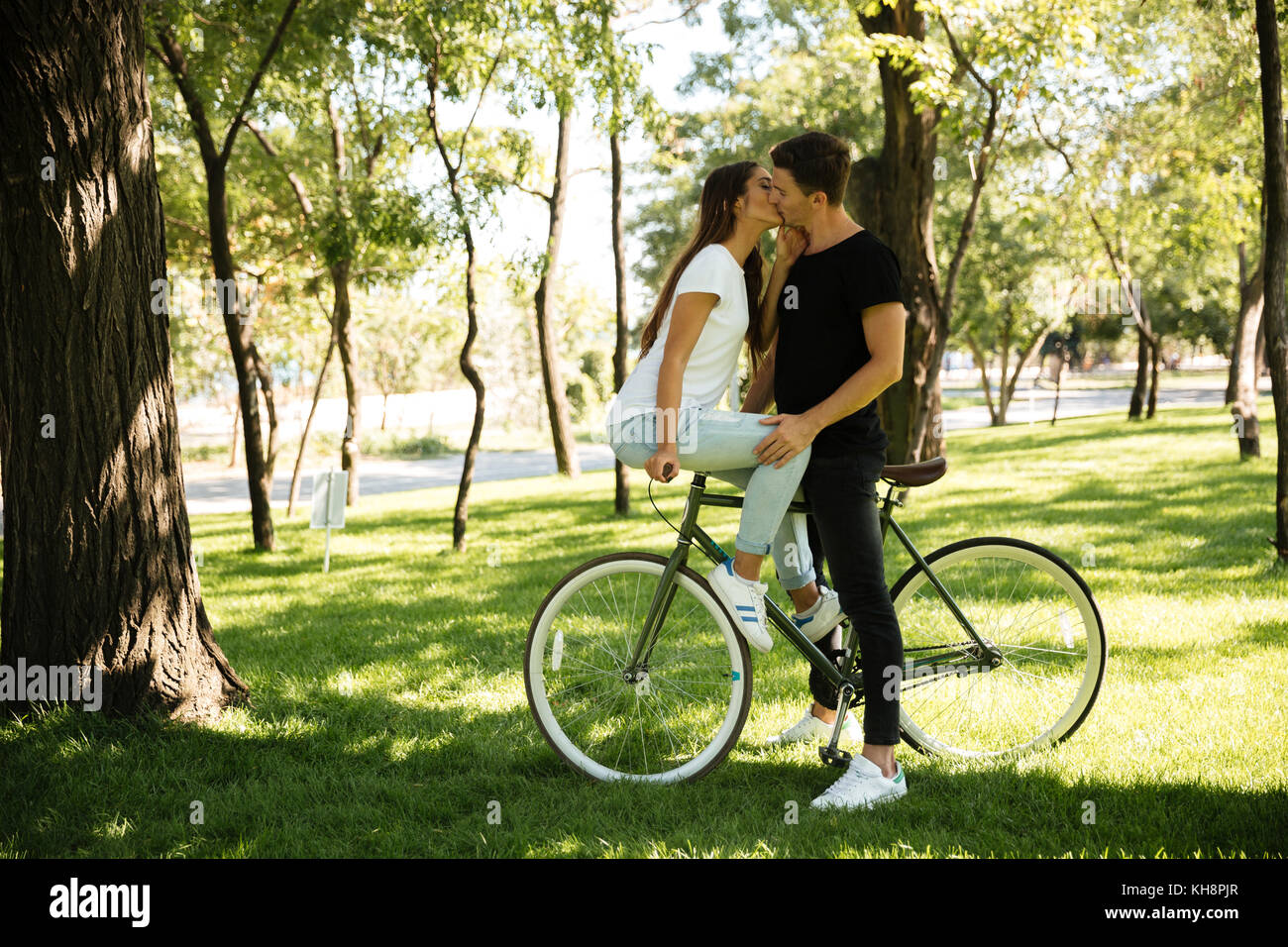 Young attractive couple kissing each other while a girl in sitting on a ...