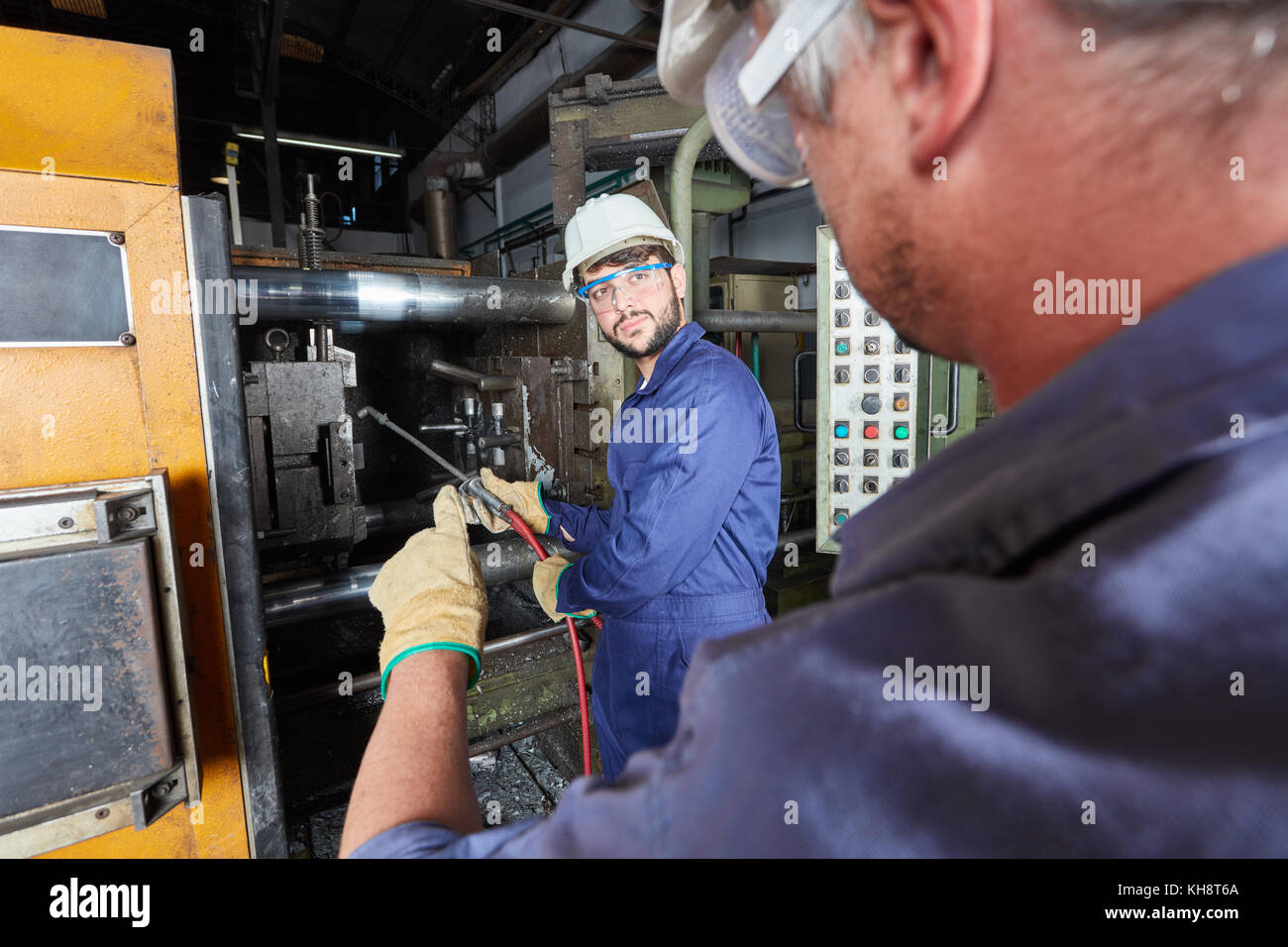 Foundry workers manufacturing metal workpieces in metallurgy factory ...