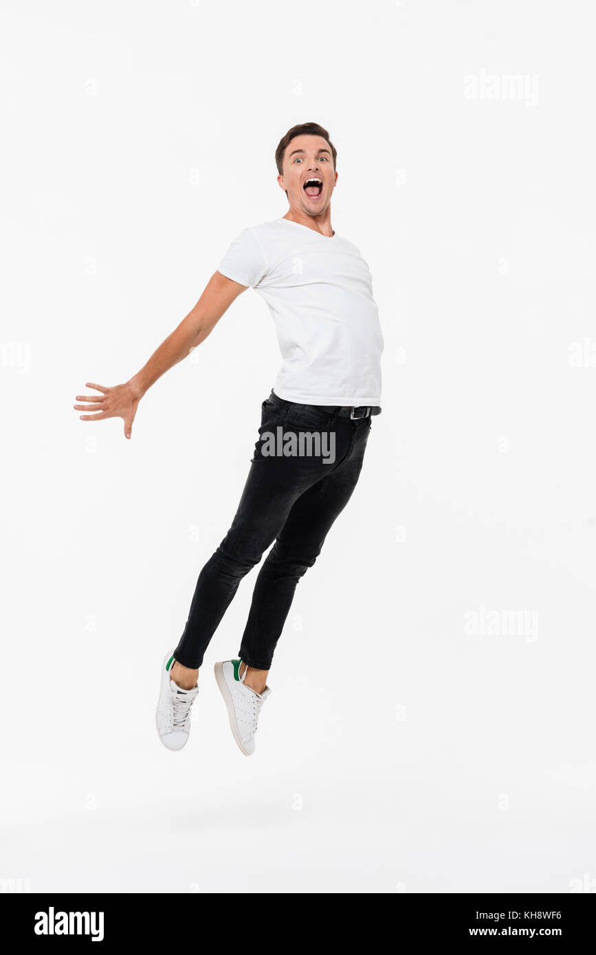 Full length portrait of a joyful amused man in white t-shirt jumping ...