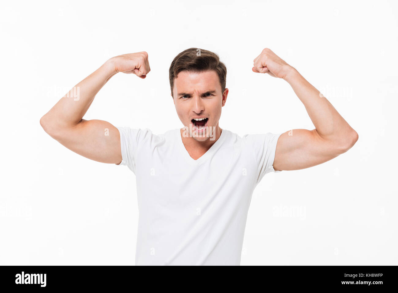 Portrait of a handsome strong man flexing his biceps and looking at ...