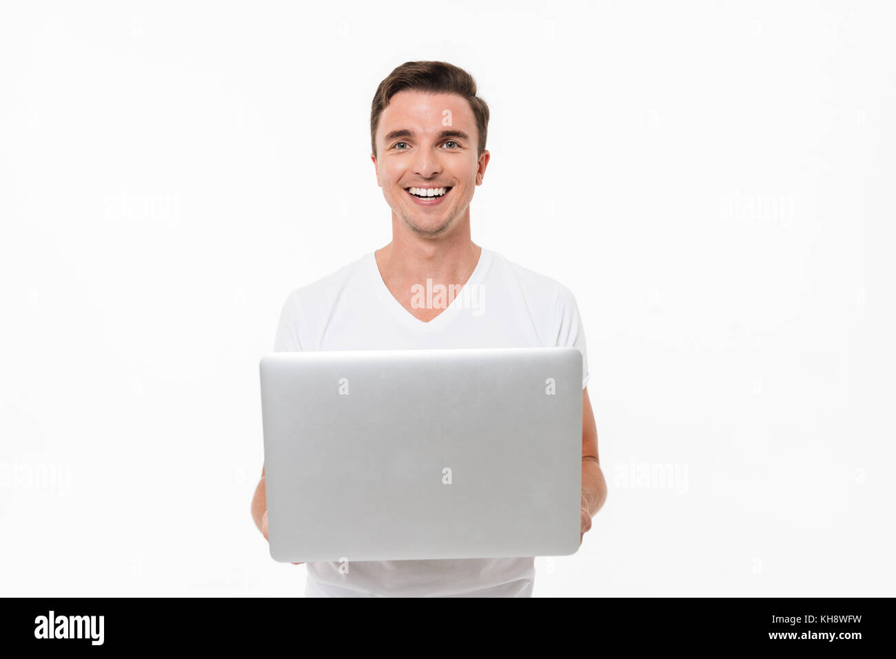 Portrait of a satisfied smiling guy working on laptop computer while ...