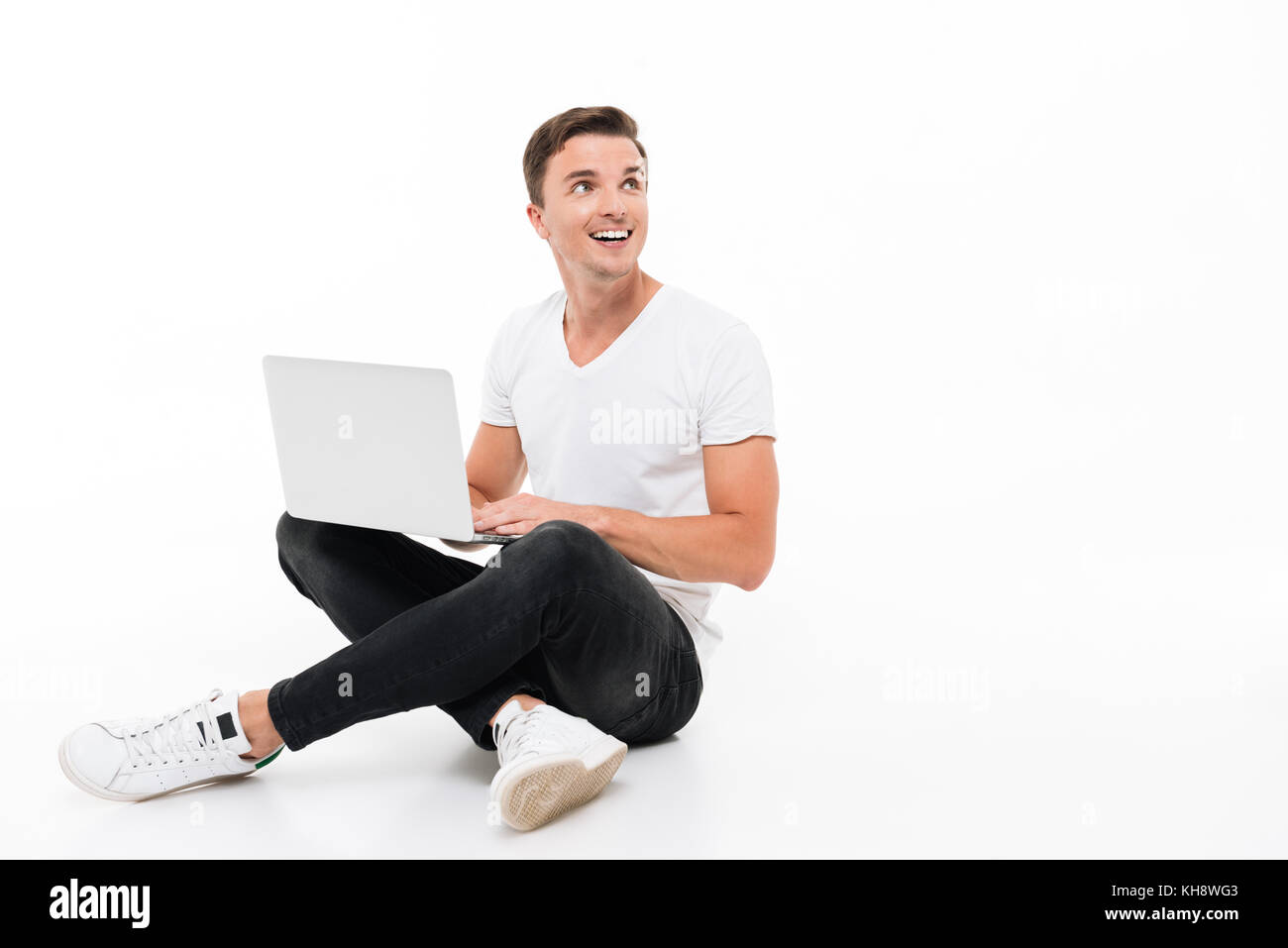 Portrait of a positive smiling man working on laptop computer while ...