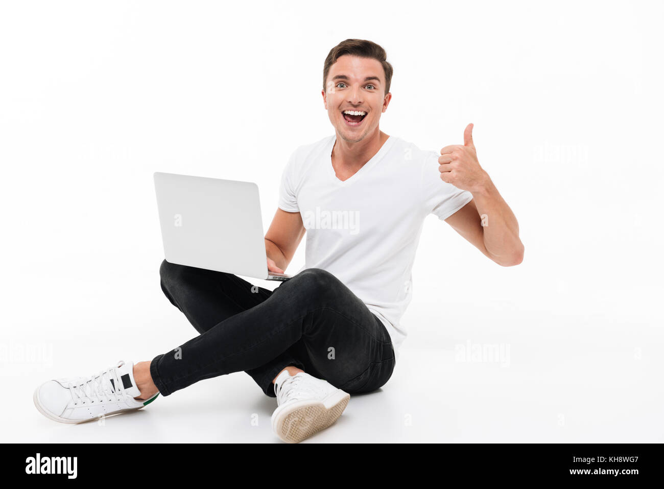 Portrait of a happy excited man holding laptop computer while sitting ...