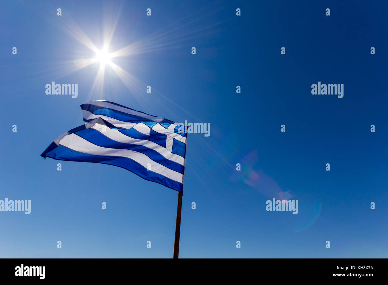 greek flag against the deep blue sky with sun and lens flair Stock ...