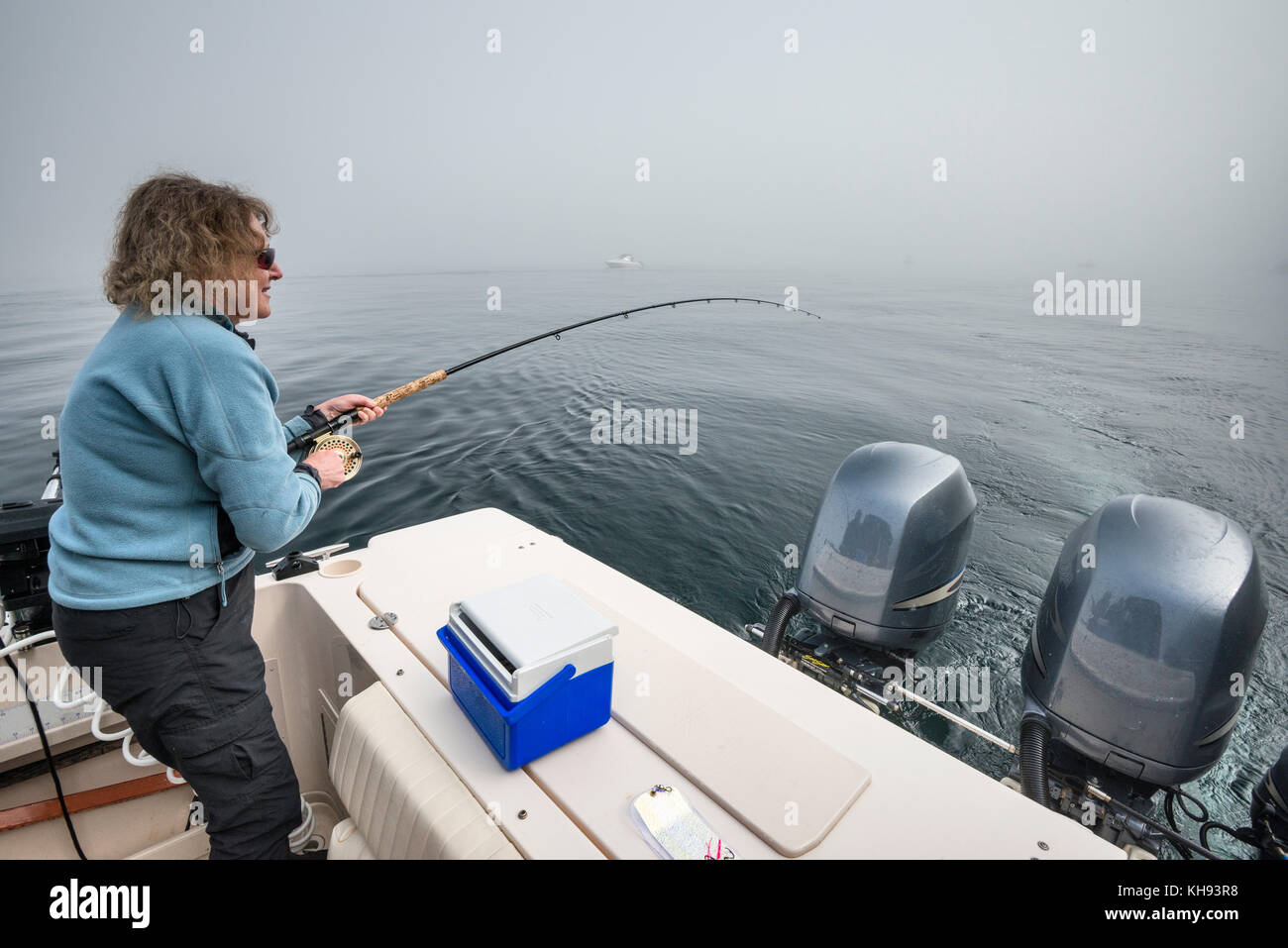 Woman with fishing rod on boat, pulling the fish out of water, other ...