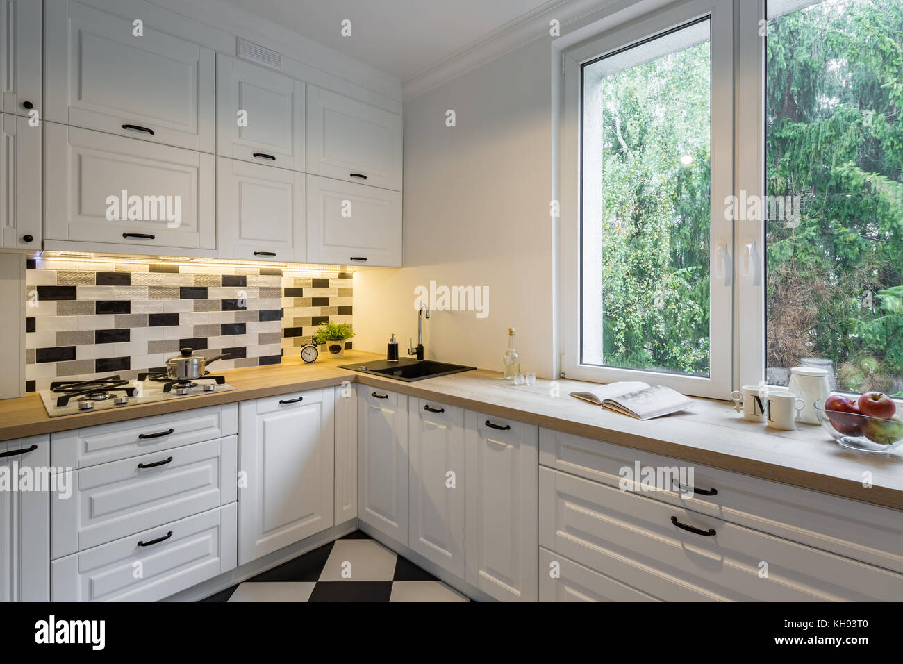 Functional kitchen with classic white cabinets and window Stock Photo ...
