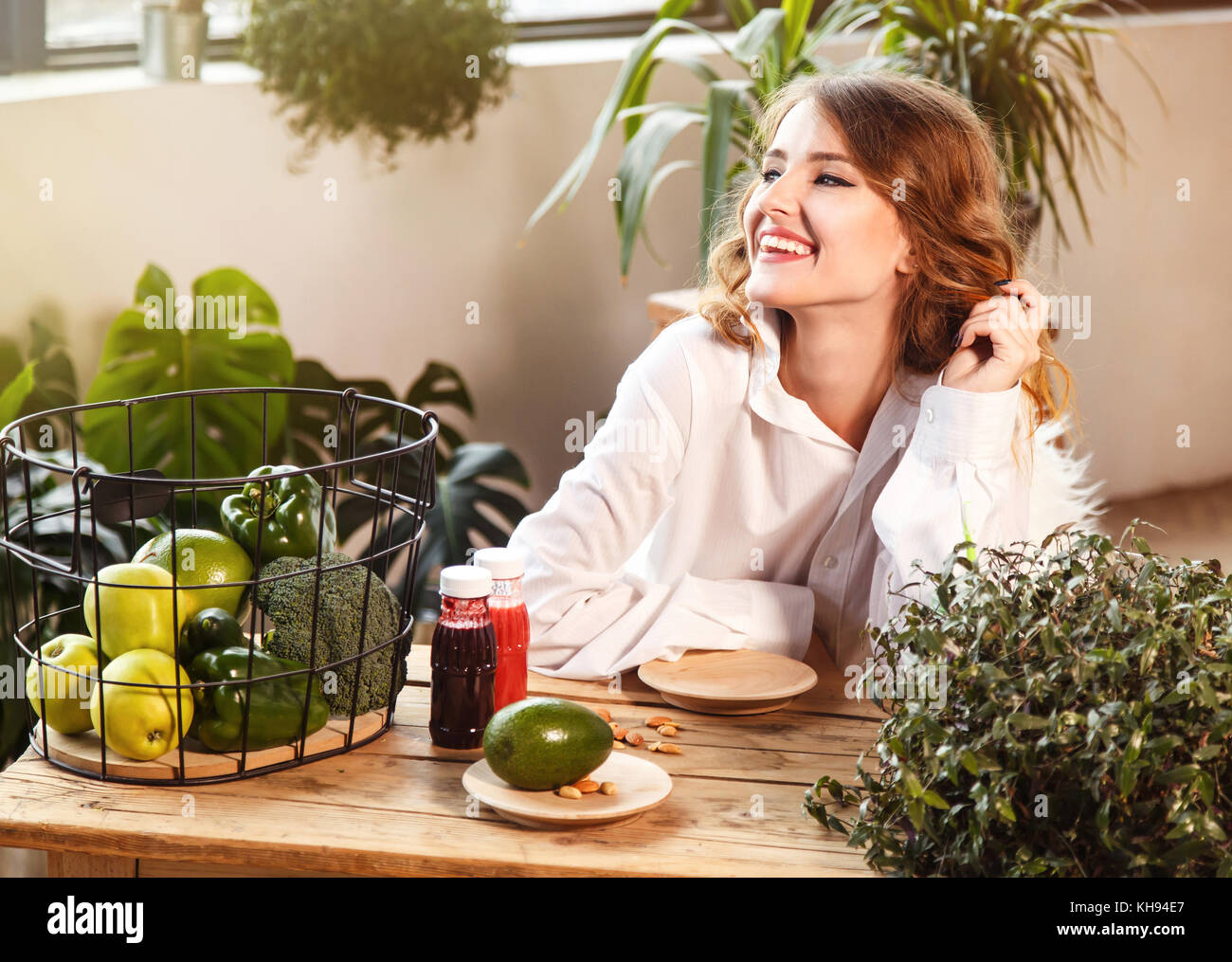Fair-haired girl sitting down at the table full of healthy food, indoor ...