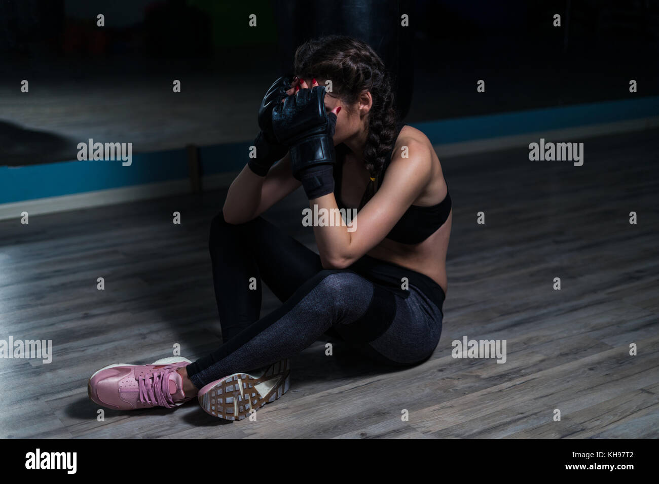 Upset young fighter boxer girl wearing boxing gloves siting on t Stock ...