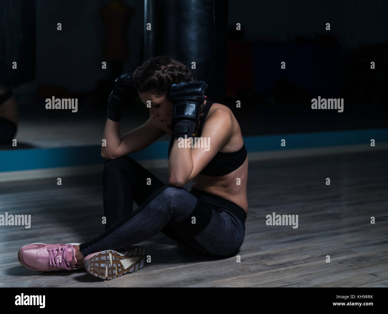 Upset young fighter boxer girl wearing boxing gloves siting on t Stock ...