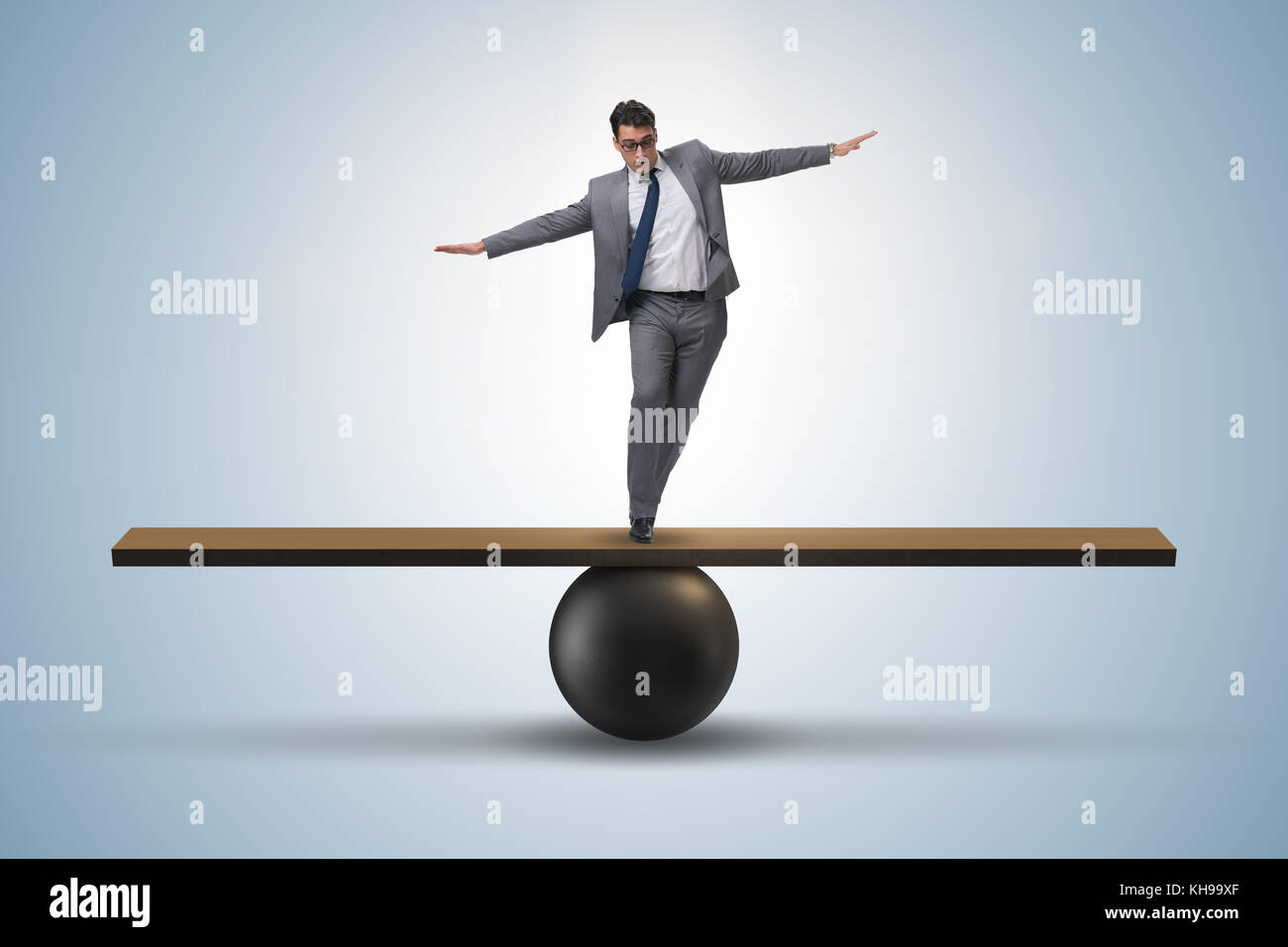 Businessman trying to balance on ball and seesaw Stock Photo - Alamy