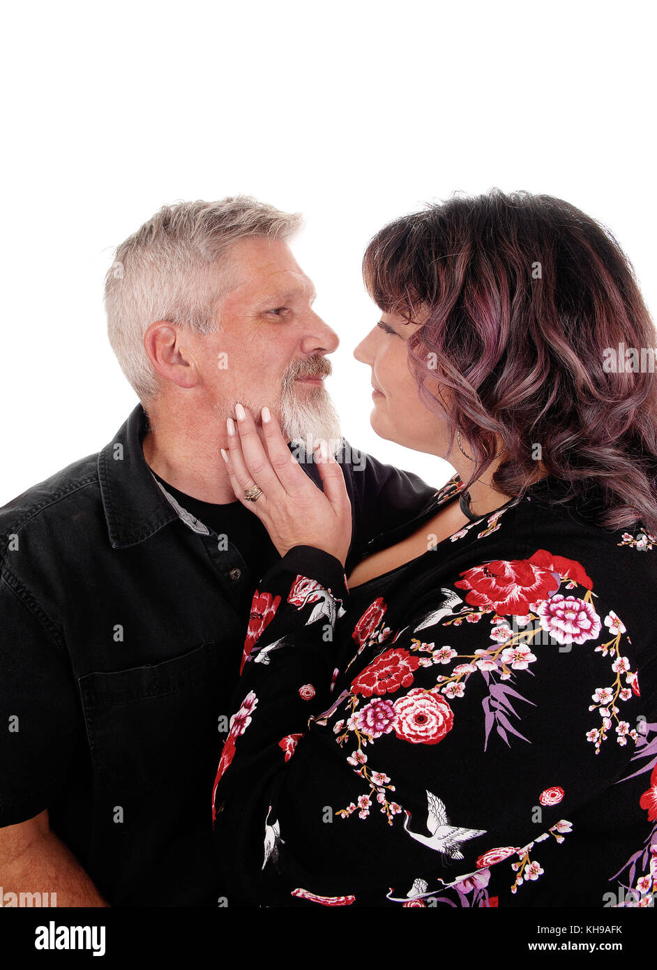 A middle age couple in a loving gesture in a closeup image, isolated ...