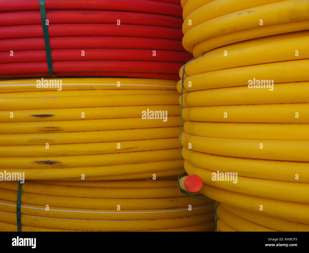 Thick electric cable's coils are bright yellow and bright red, curled ...