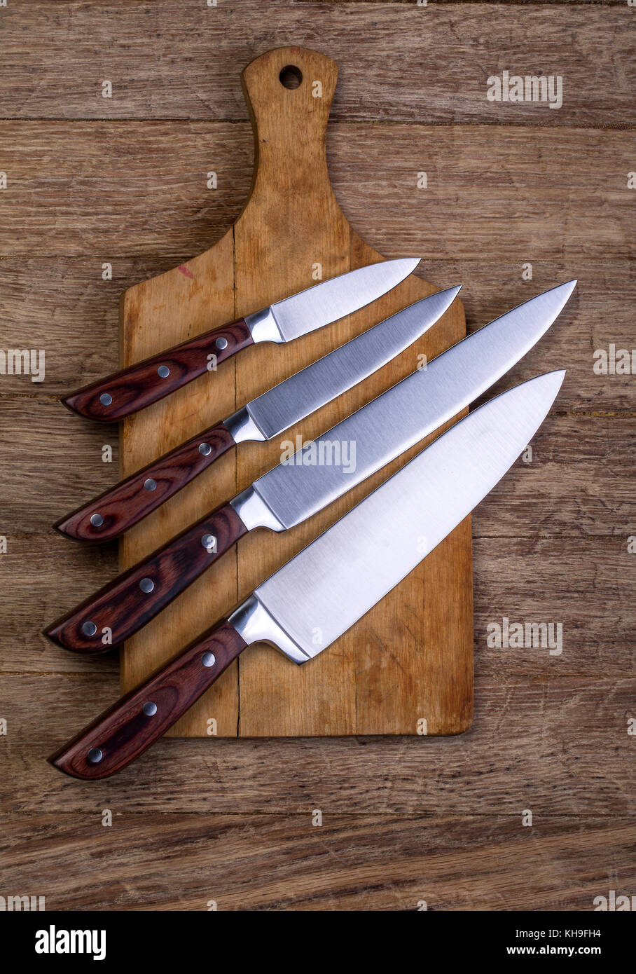 Set of kitchen knifes on wooden cutting board on old wooden table Stock ...