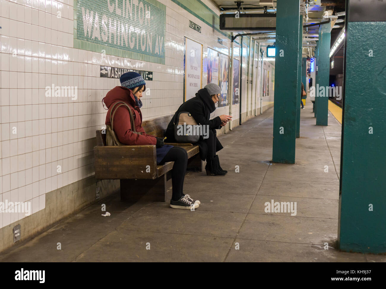 Subway riders on their electronic devices wait for a train at the ...