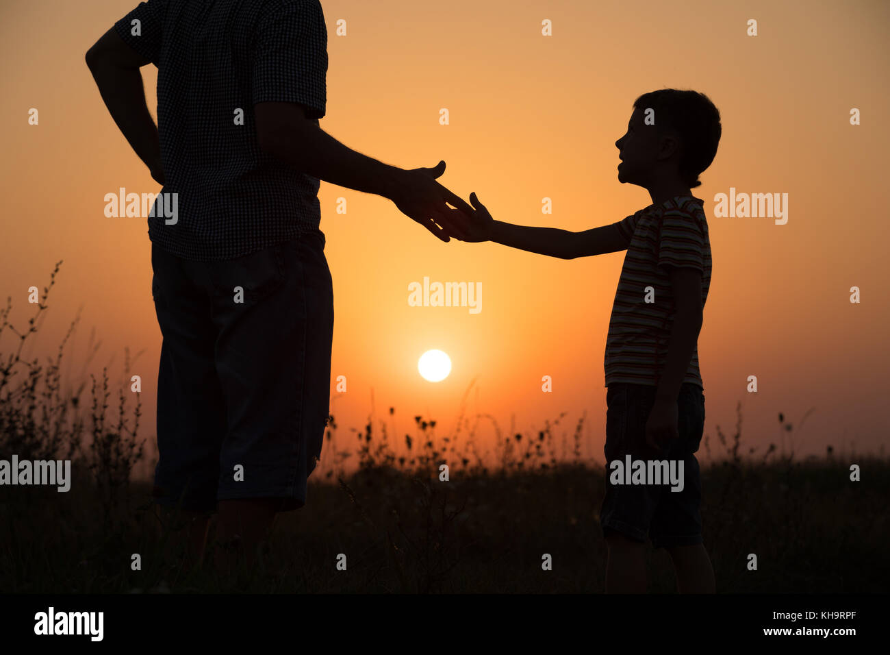 Father and son playing in the park at the sunset time. People having ...