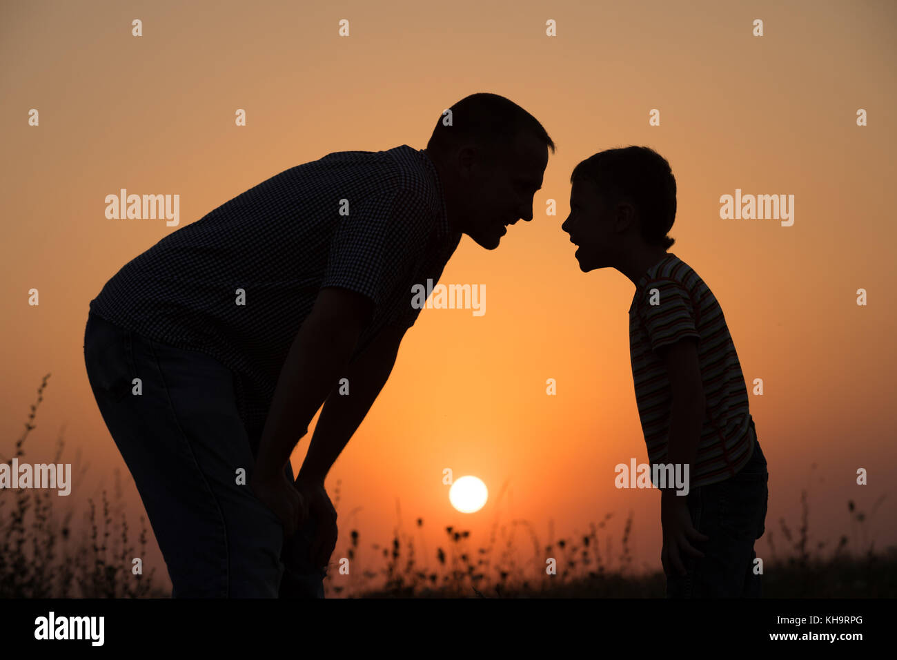Father and son playing in the park at the sunset time. People having ...