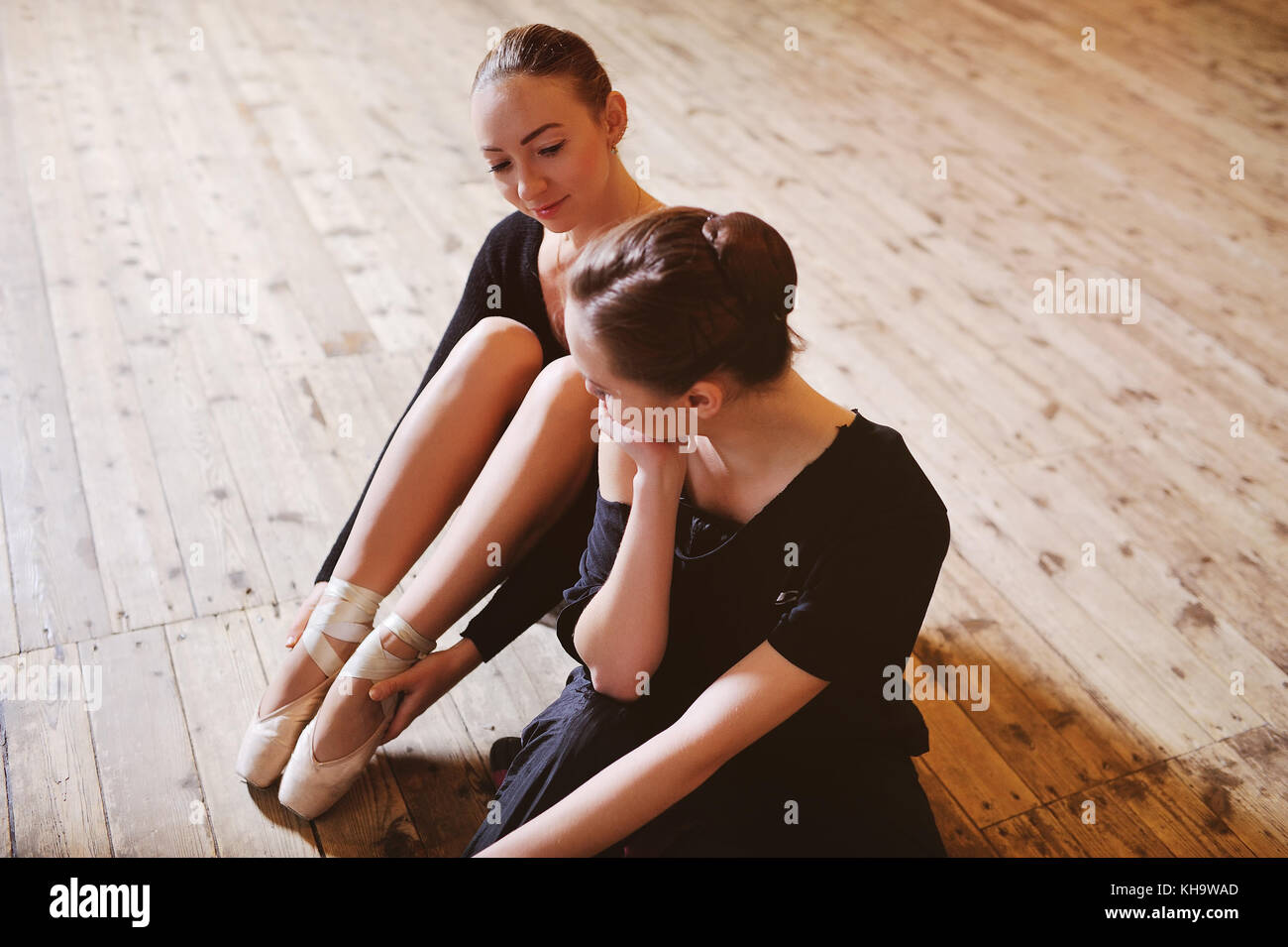 two ballerinas talking and smiling sitting on a wooden floor Stock ...
