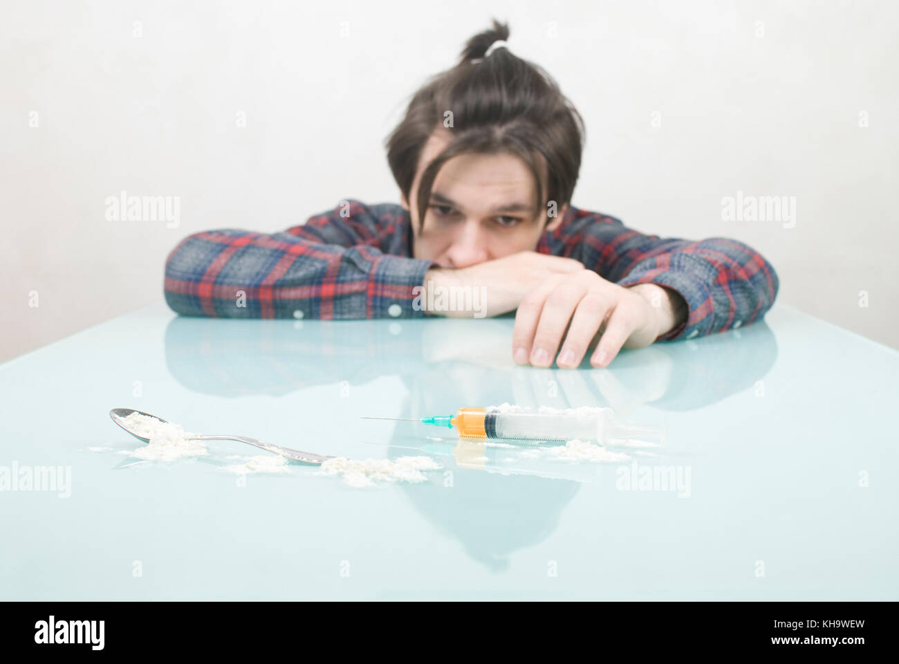 young guy looks at a syringe with heroin Stock Photo - Alamy