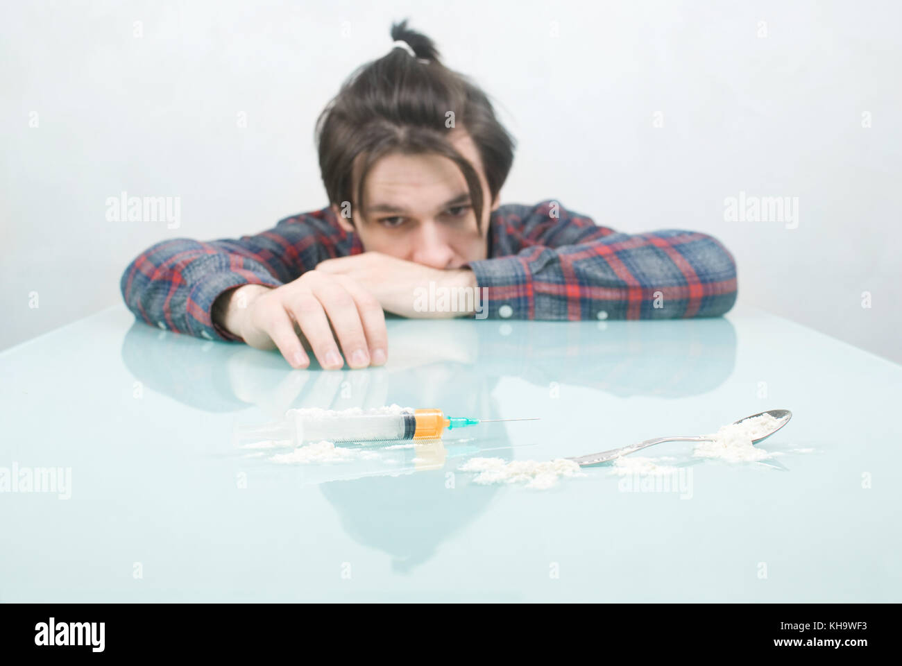young guy looks at a syringe with heroin Stock Photo - Alamy