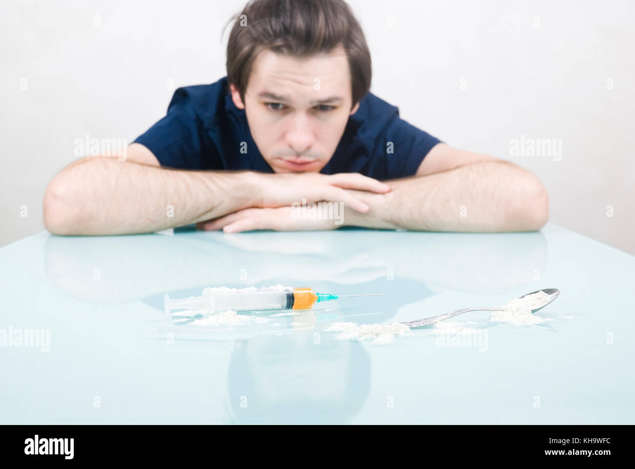 young guy looks at a syringe with heroin Stock Photo - Alamy