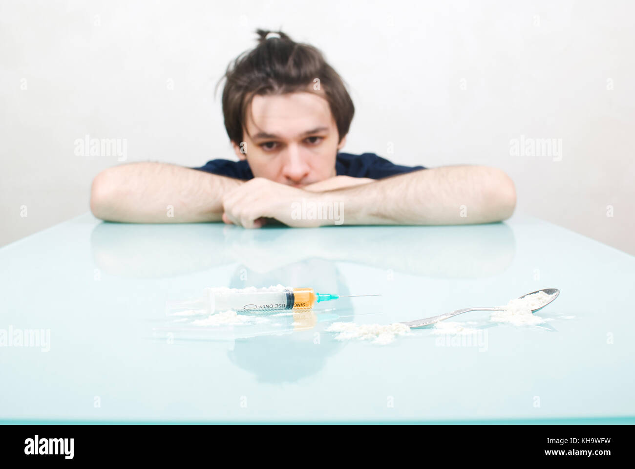 young guy looks at a syringe with heroin Stock Photo - Alamy