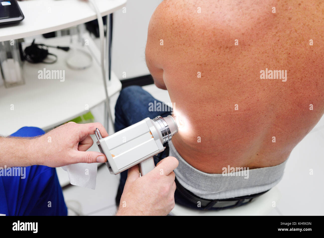 The dermatologist examines the moles or acne of the patient with a ...