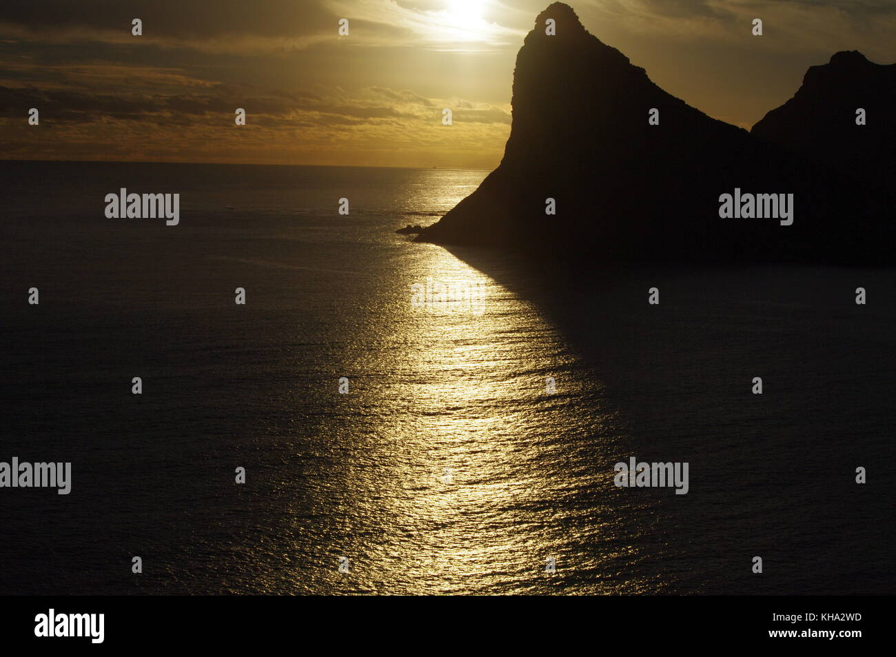 Eerie sunset showing streak of light over ocean with black mountain ...