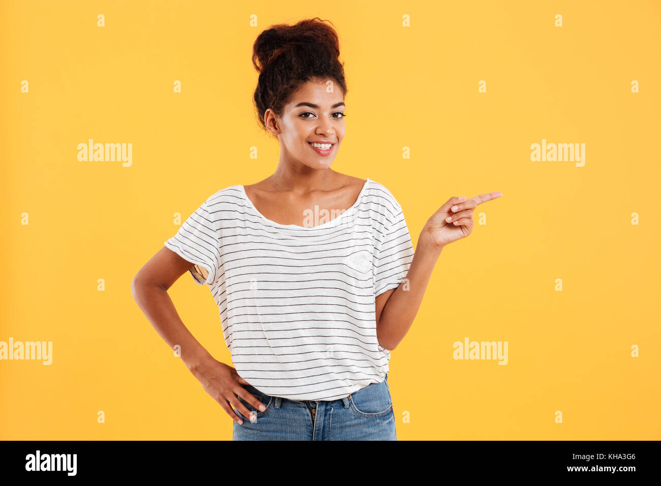 Young cheerful lady pointing at copy space and smiling isolated over ...