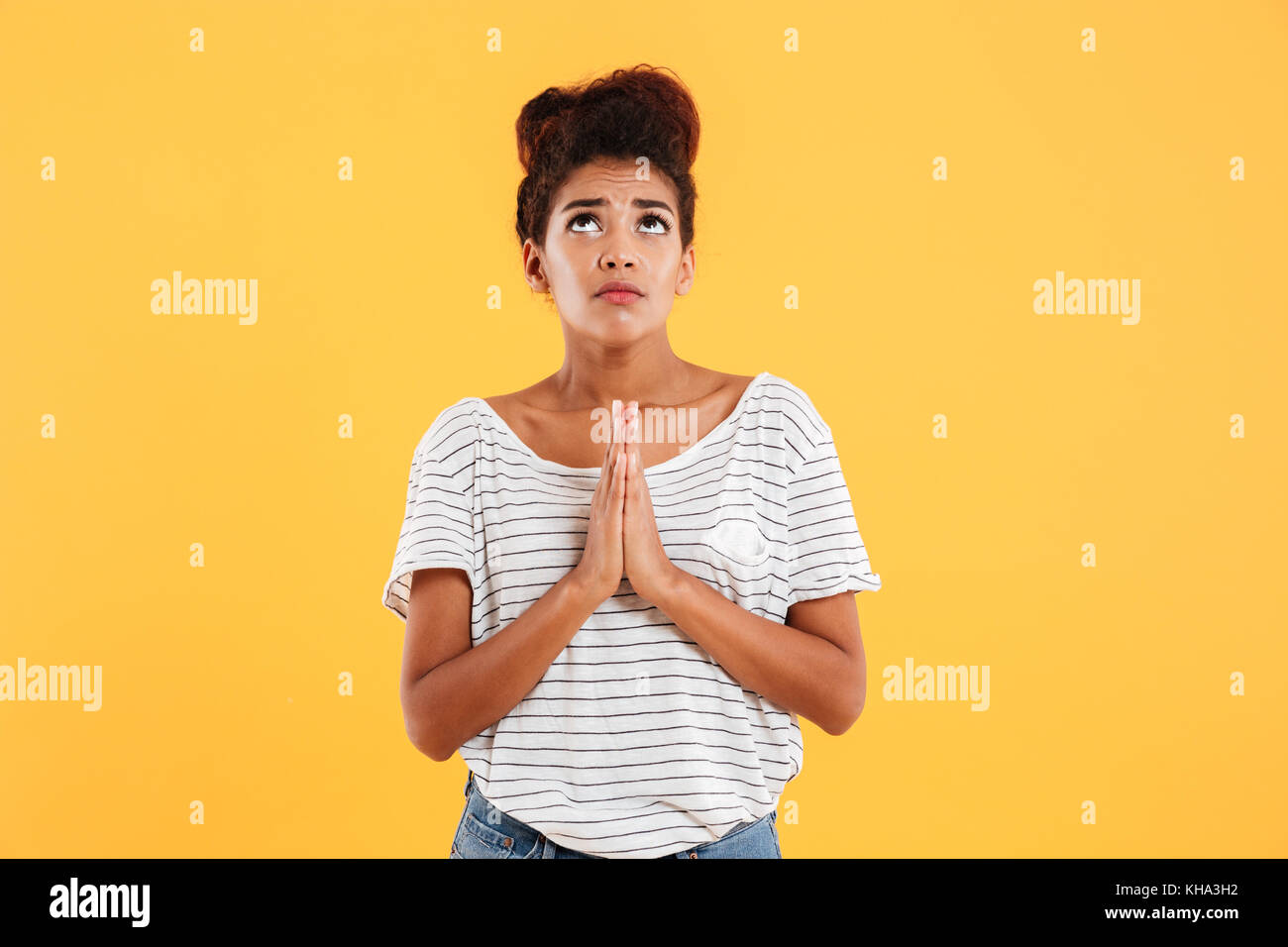 Young nervous pretty african lady looking up and praying while holding ...