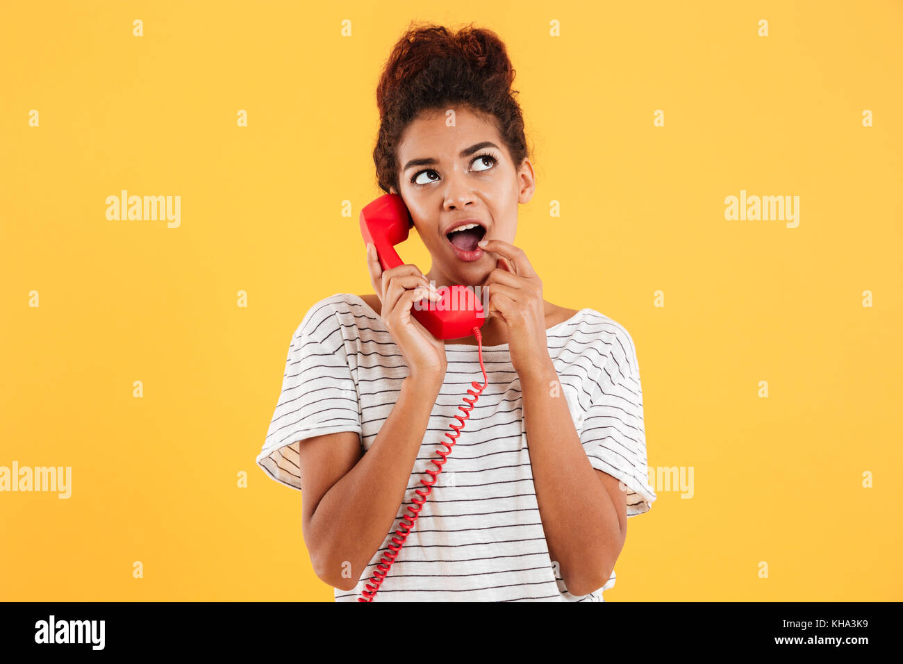 Smiling pretty young lady looking up with opened mouth and holding red ...