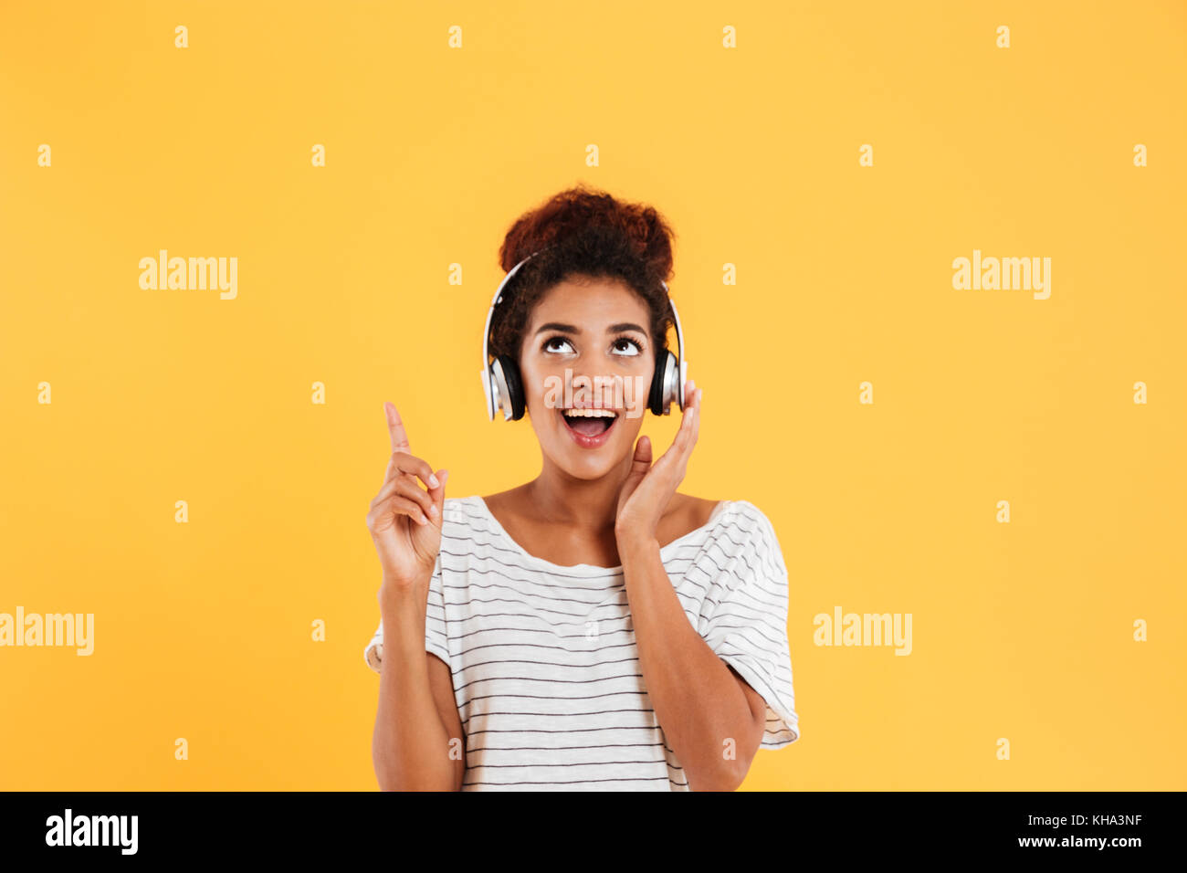 Happy african lady listening music in headphones while looking and ...