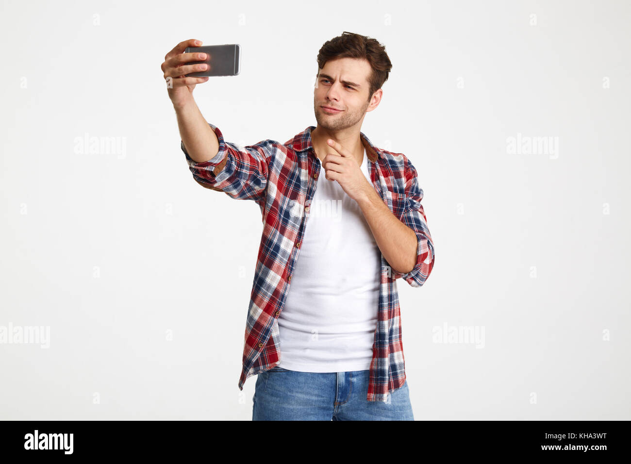 Portrait of an attractive young man taking a selfie while standing and ...