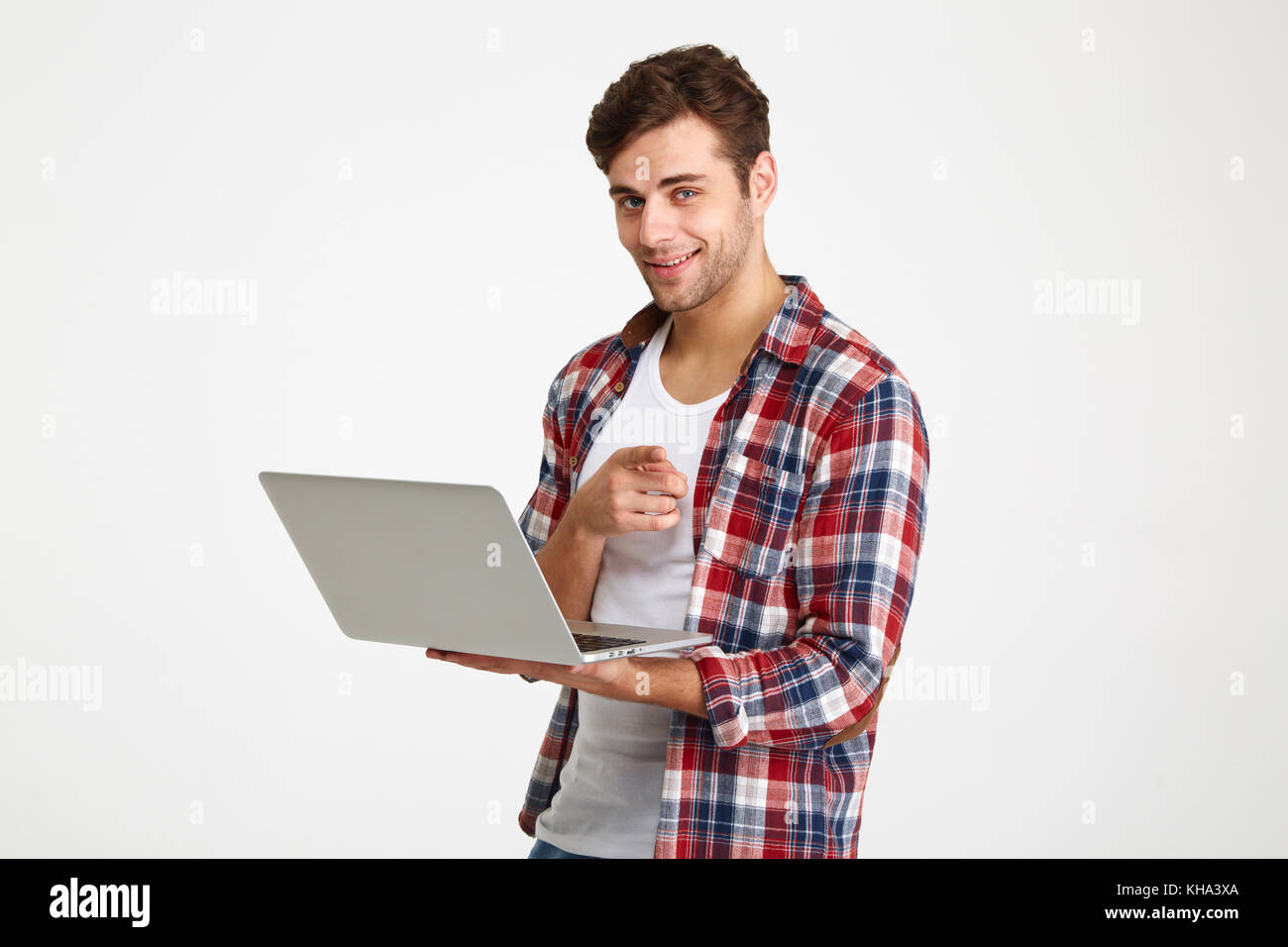 Portrait of a confident young man holding laptop computer while ...