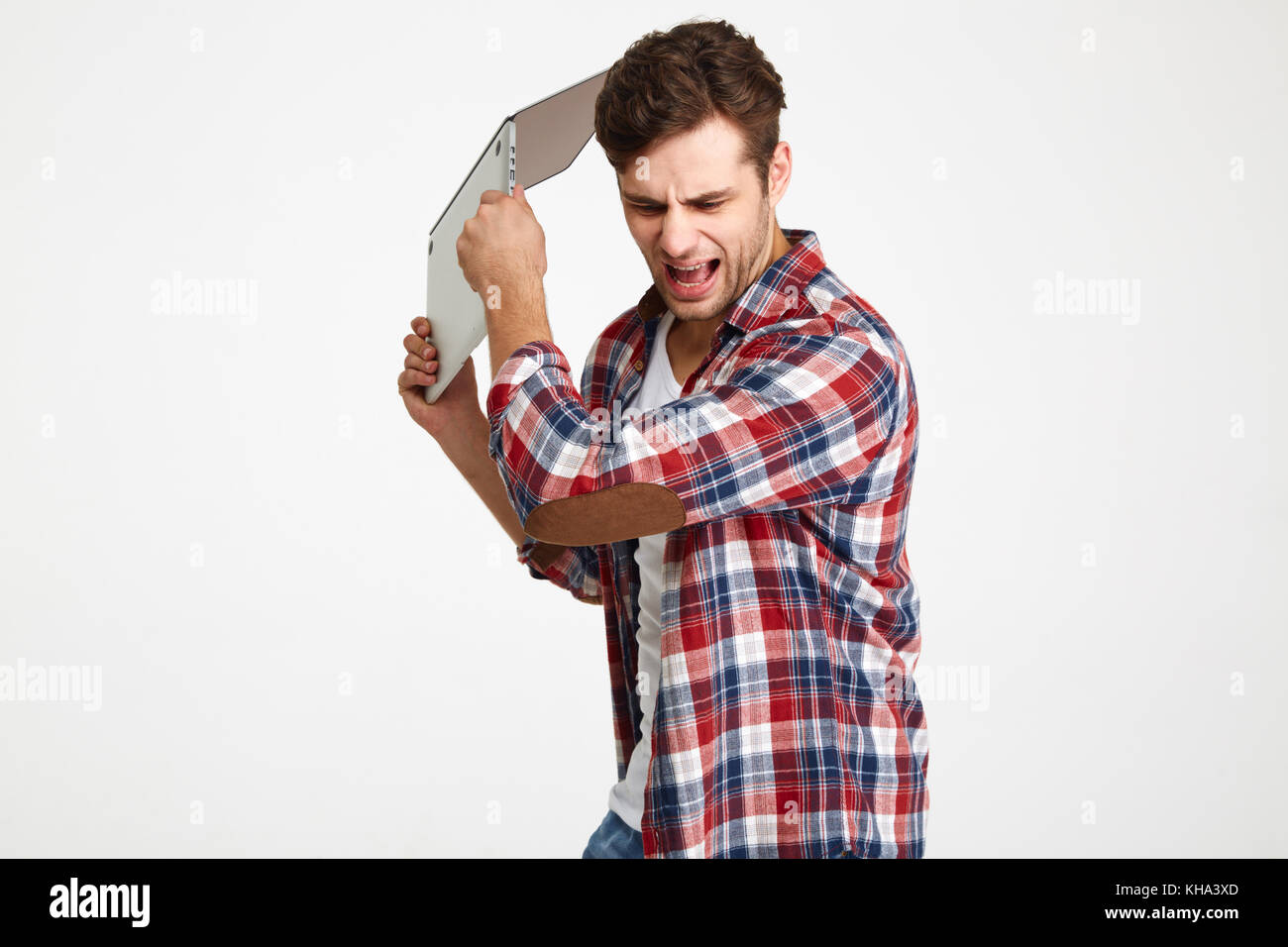 Portrait of an angry furious man throwing his laptop computer isolated ...