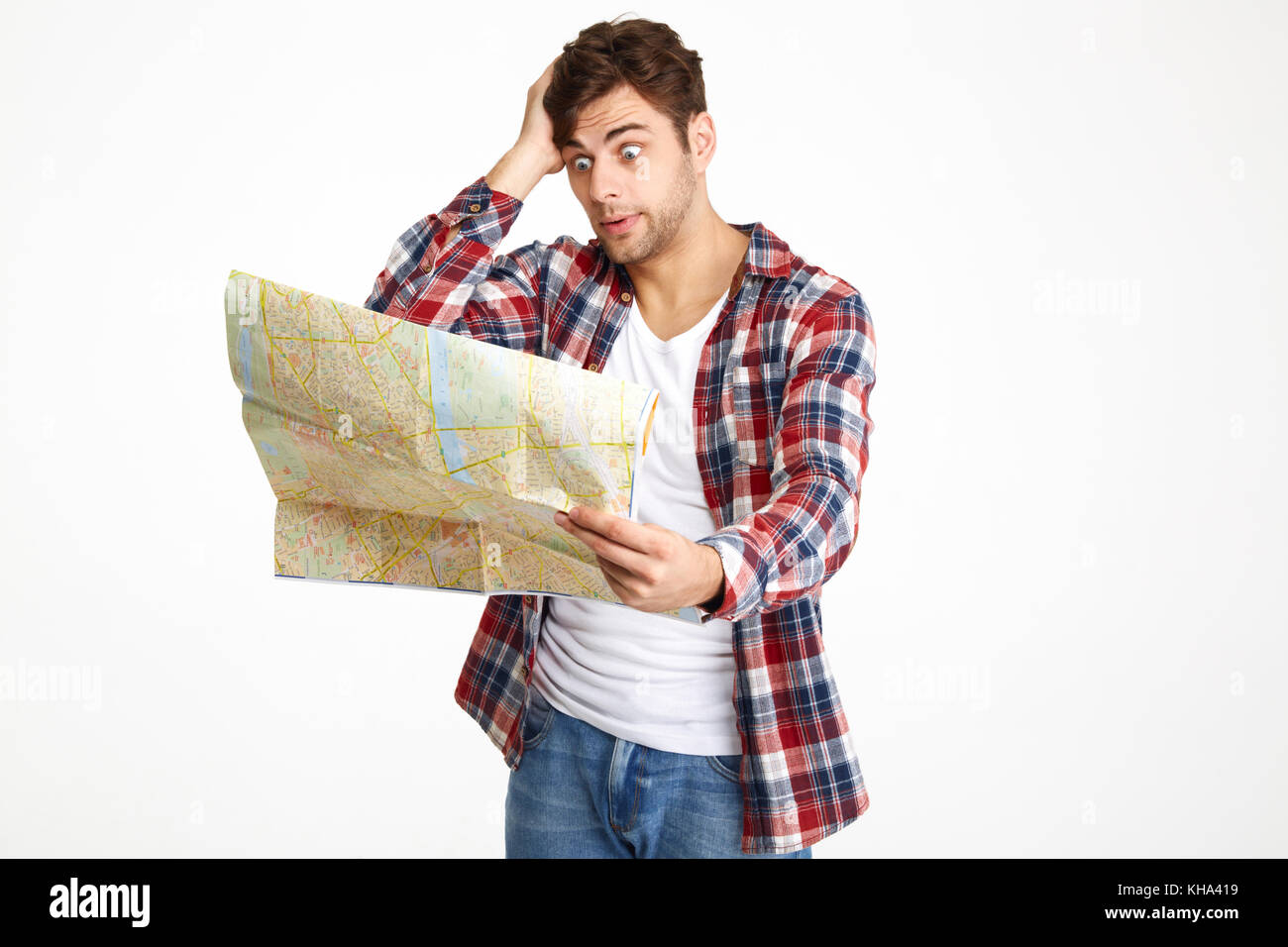 Portrait of a mixed-up young man looking at travel map isolated over ...