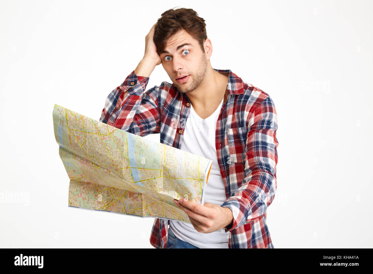 Portrait of a bewildered young man holding travel map and looking at ...