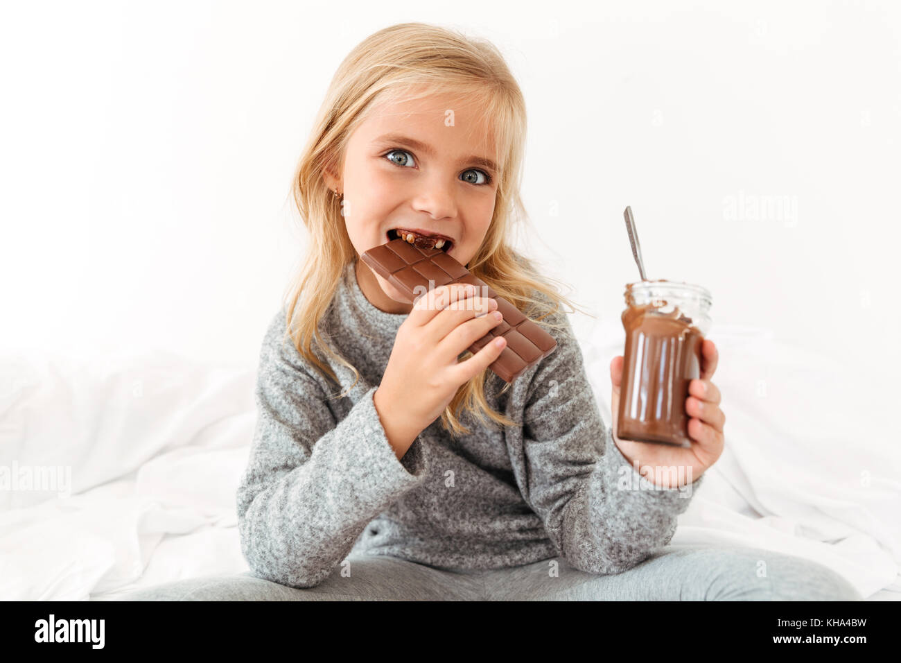 Close-up photo of funny girl eating chocolate bar looking at camera ...