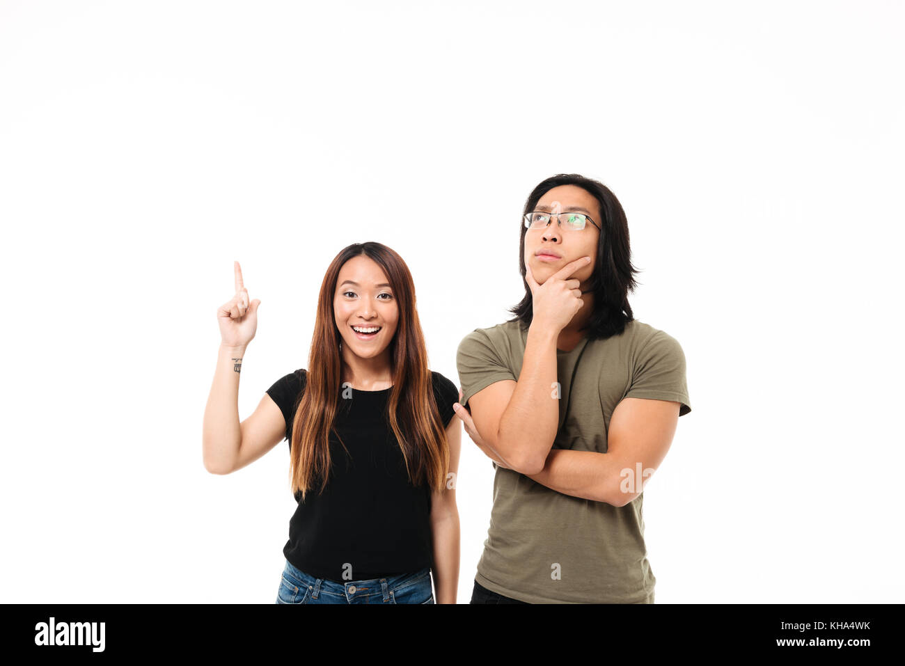 Portrait of a thoughtful smiling asian couple pointing finger up and ...