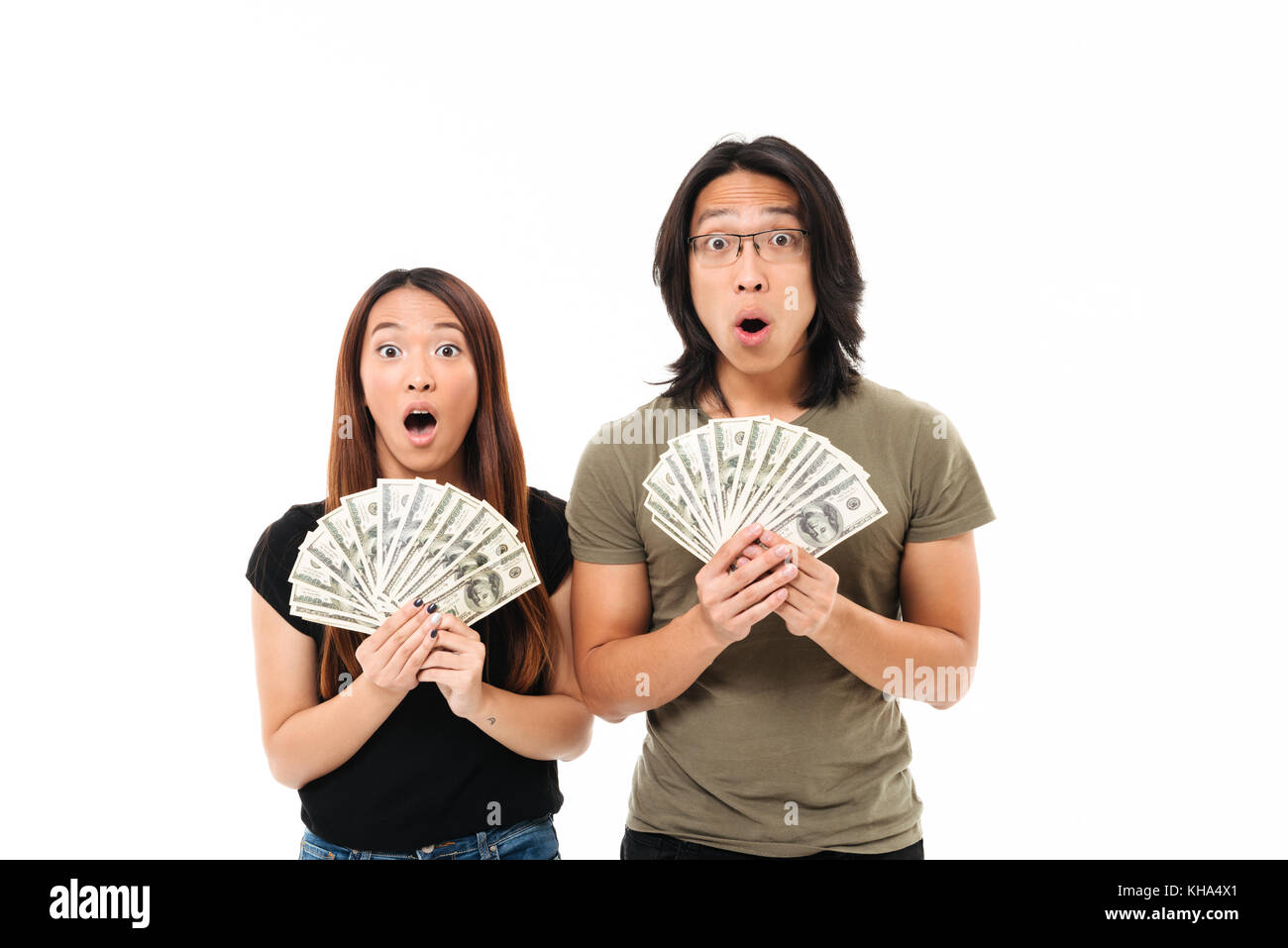 Portrait of a surprised shocked asian couple holding bunch of money ...