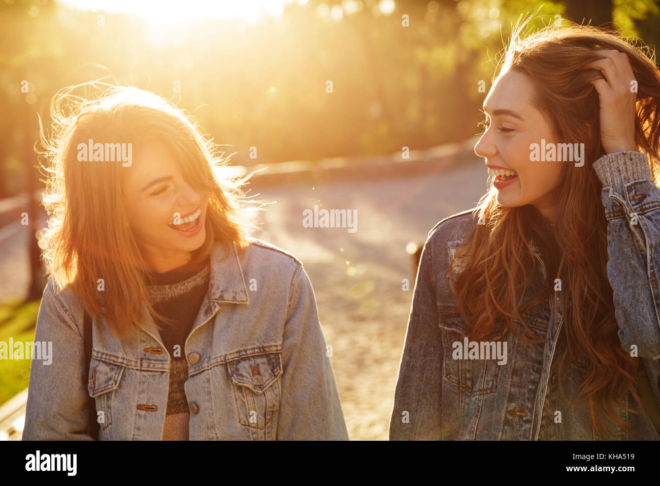 Two happy friends talking and laughing in sunny park Stock Photo - Alamy