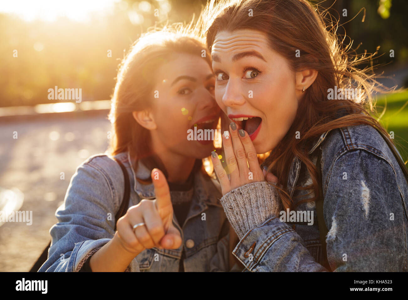 Portrait of a smiling happy girl telling a secret to her girlfriend ...