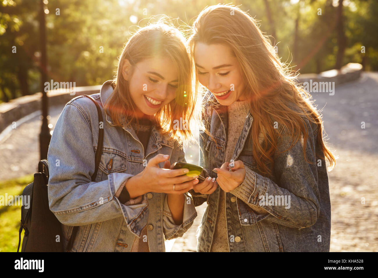 Two happy female best friends using smartphone in sunny park Stock ...