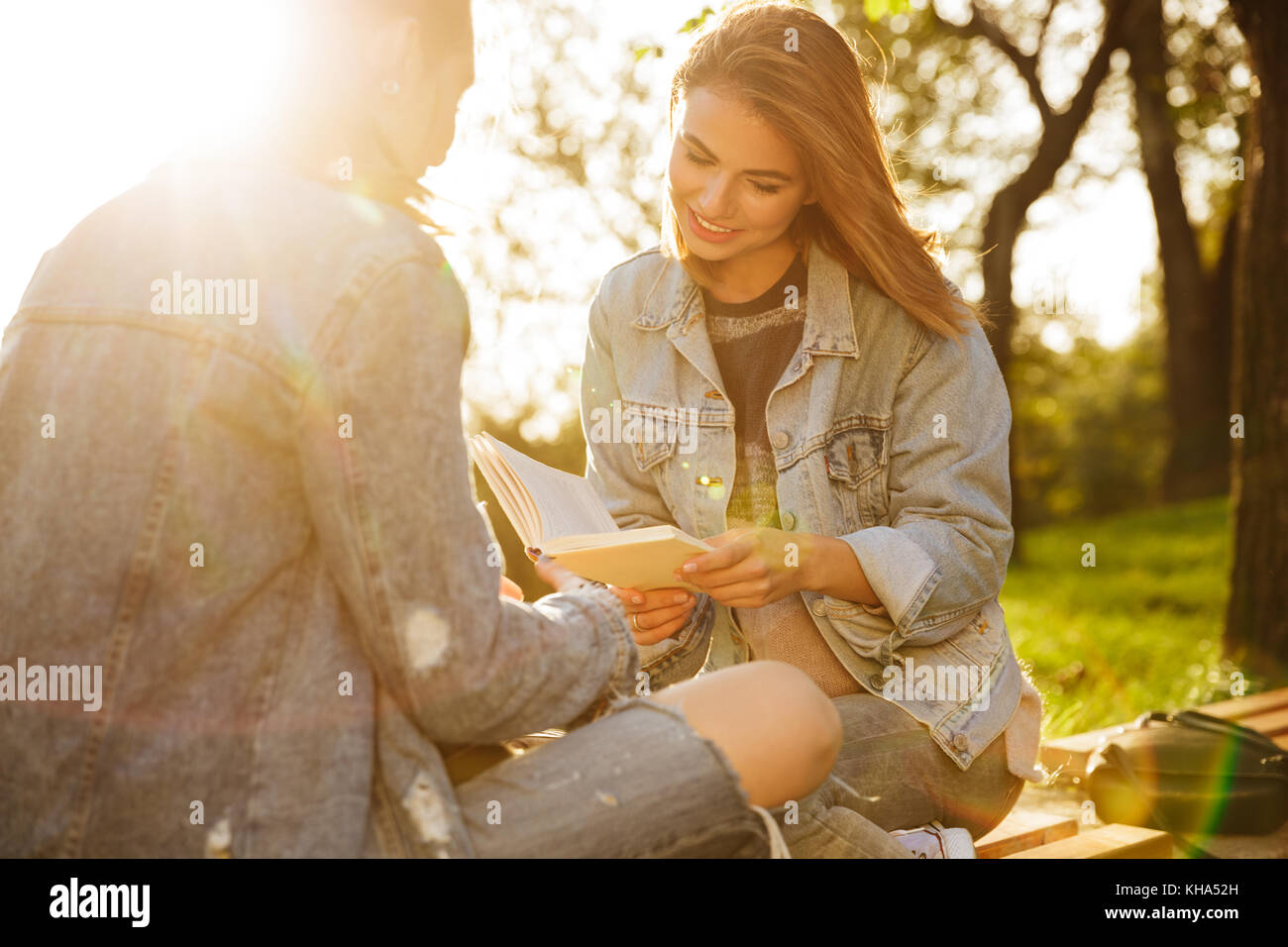 Two young girls in casual wear reading books in sunny park Stock Photo ...