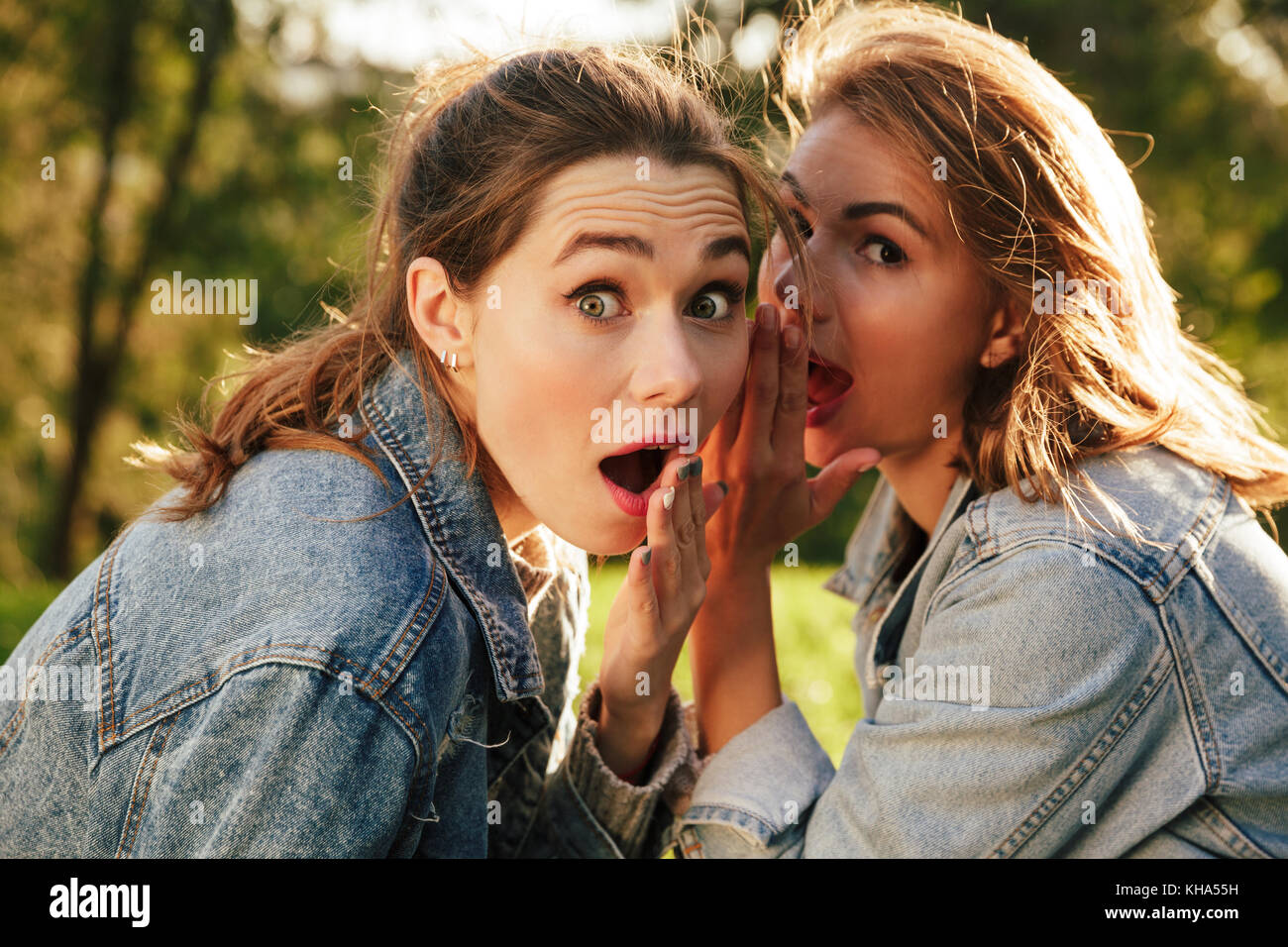 Close-up portrait of two charming female friends sharing gossips in ...